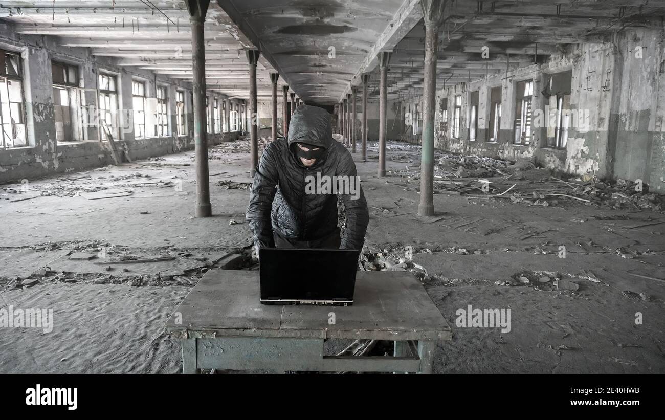 Hacker and laptop meaning safety data. Cyberterrorist in an abandoned ...