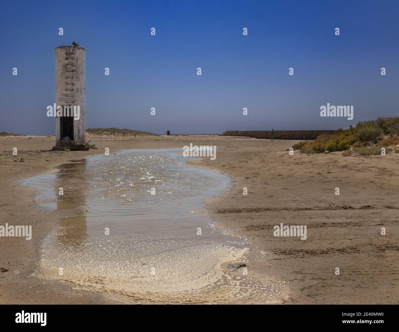 Selective focus shot of a small pond on a sandy beach with an ancient ...