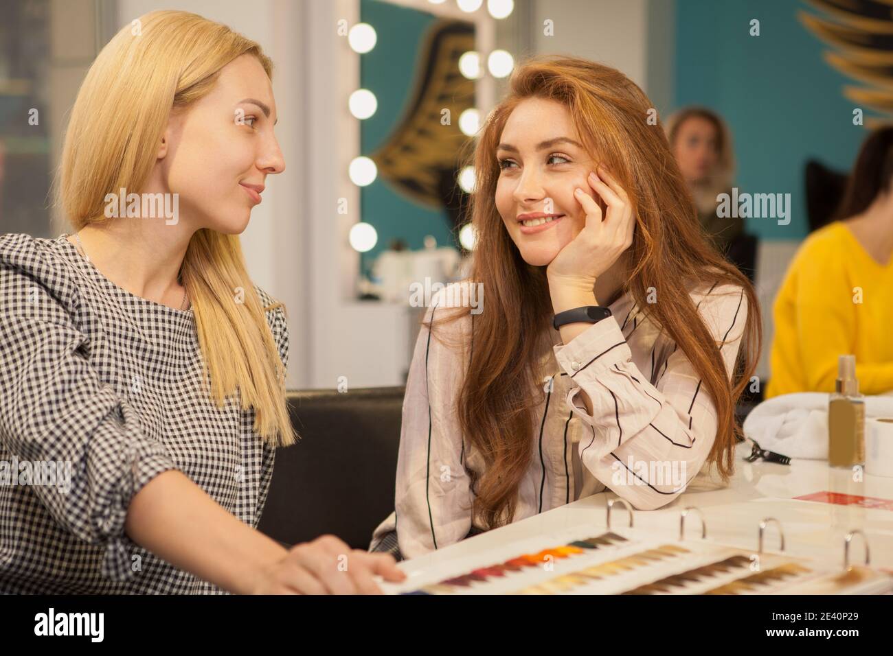 Two lovely female friends talking at the beauty salon. Beautiful long ...