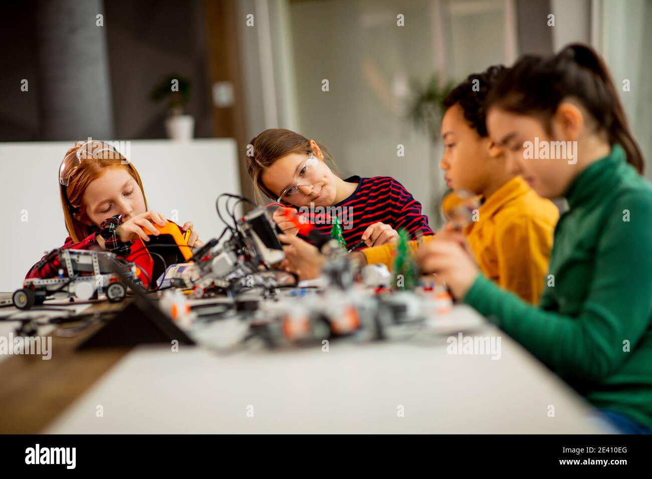 Group of happy kids programming electric toys and robots at robotics ...