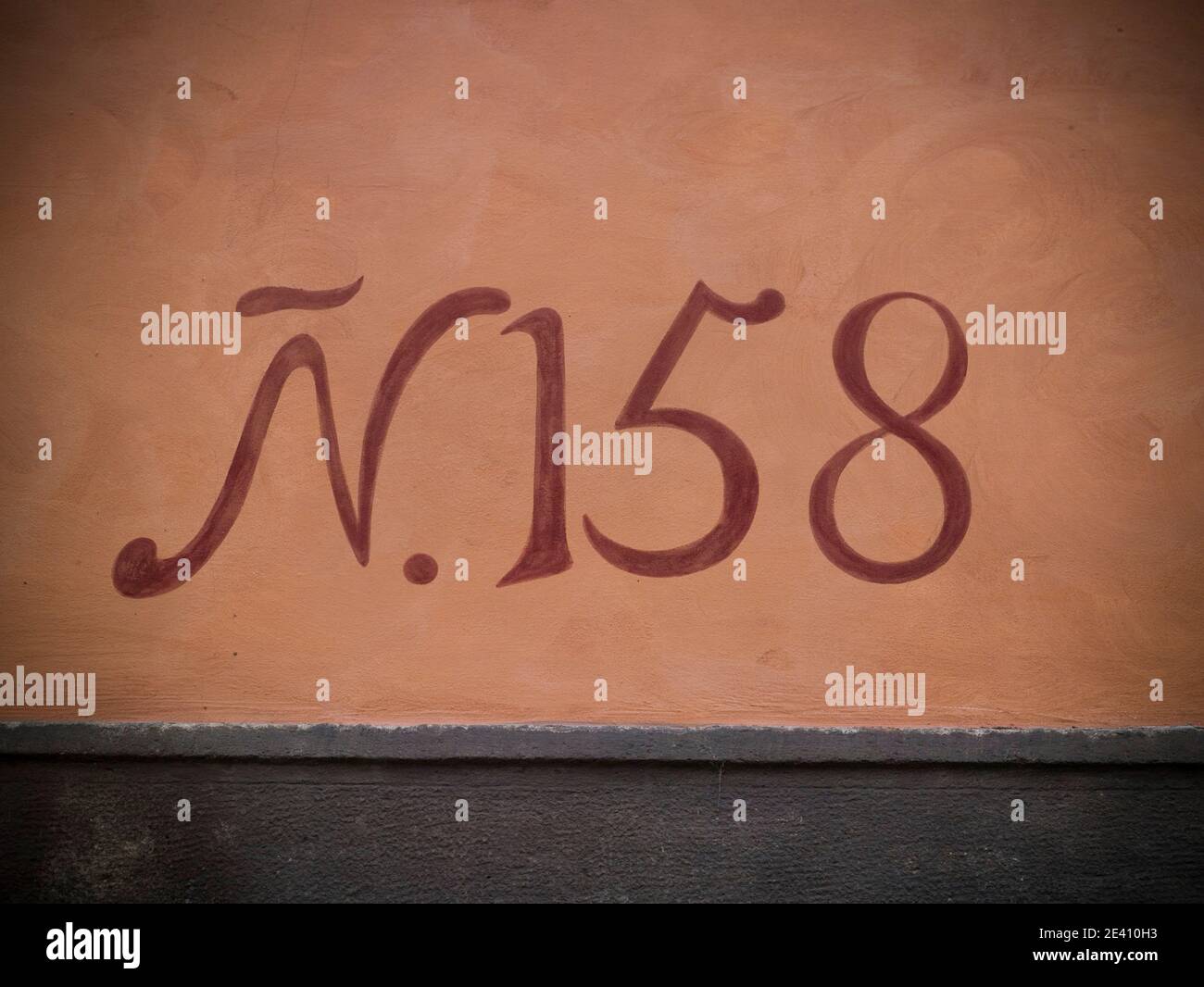 Painted house number on a terracotta coloured rendered wall Stock Photo ...