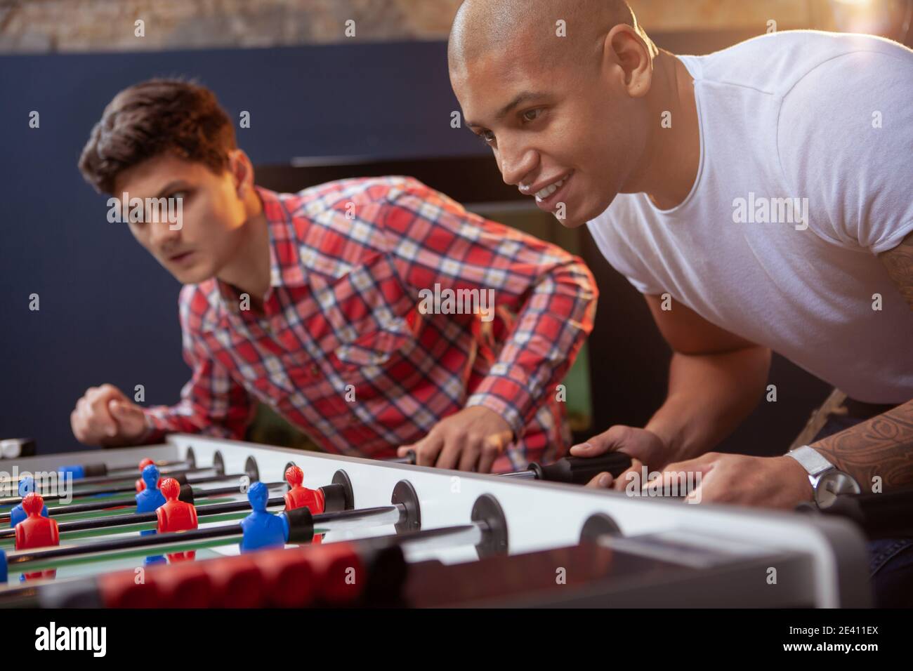 Handsome African man smiling, playing table football with his friend ...