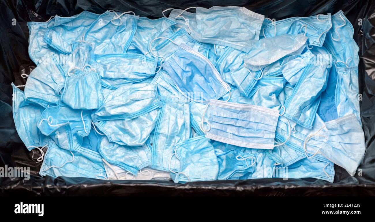 Discarded medical waste mask on virus banner in garbage can ...