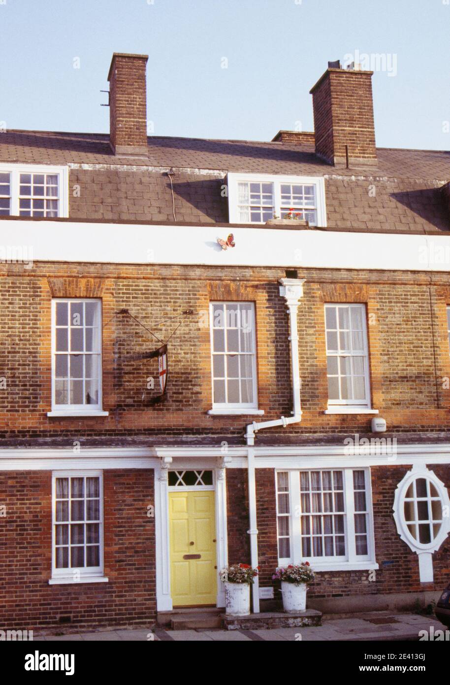 Brick georgian terrace with bright yellow door; oval window and potted ...