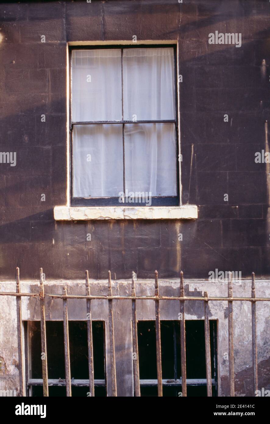 Ground floor window & basement area, broken railings, sooty uncleaned ...