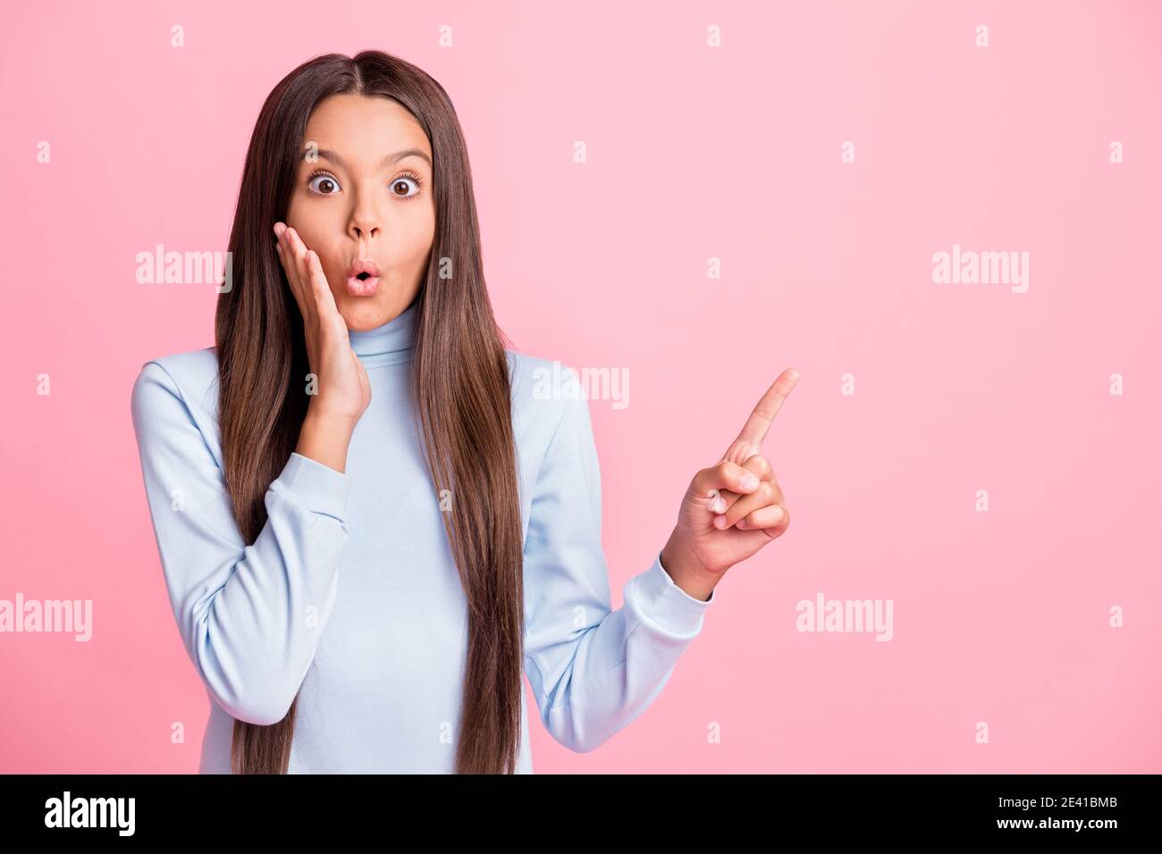 Portrait of school girl shocked hand on cheek indicate finger empty ...