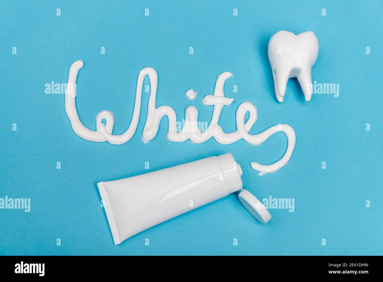 Top view of white lettering near tube of toothpaste and tooth model on ...