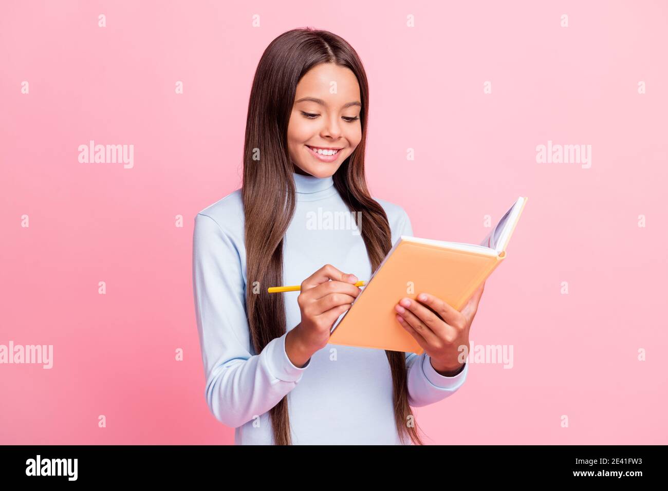 Portrait of lovely focused cheery brown-haired girl writing notes in ...
