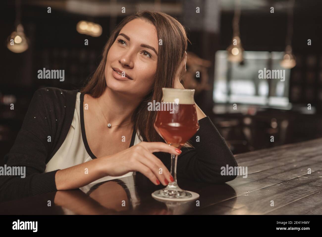 Lovely attractive woman relaxing at the pub, having delicious beer ...