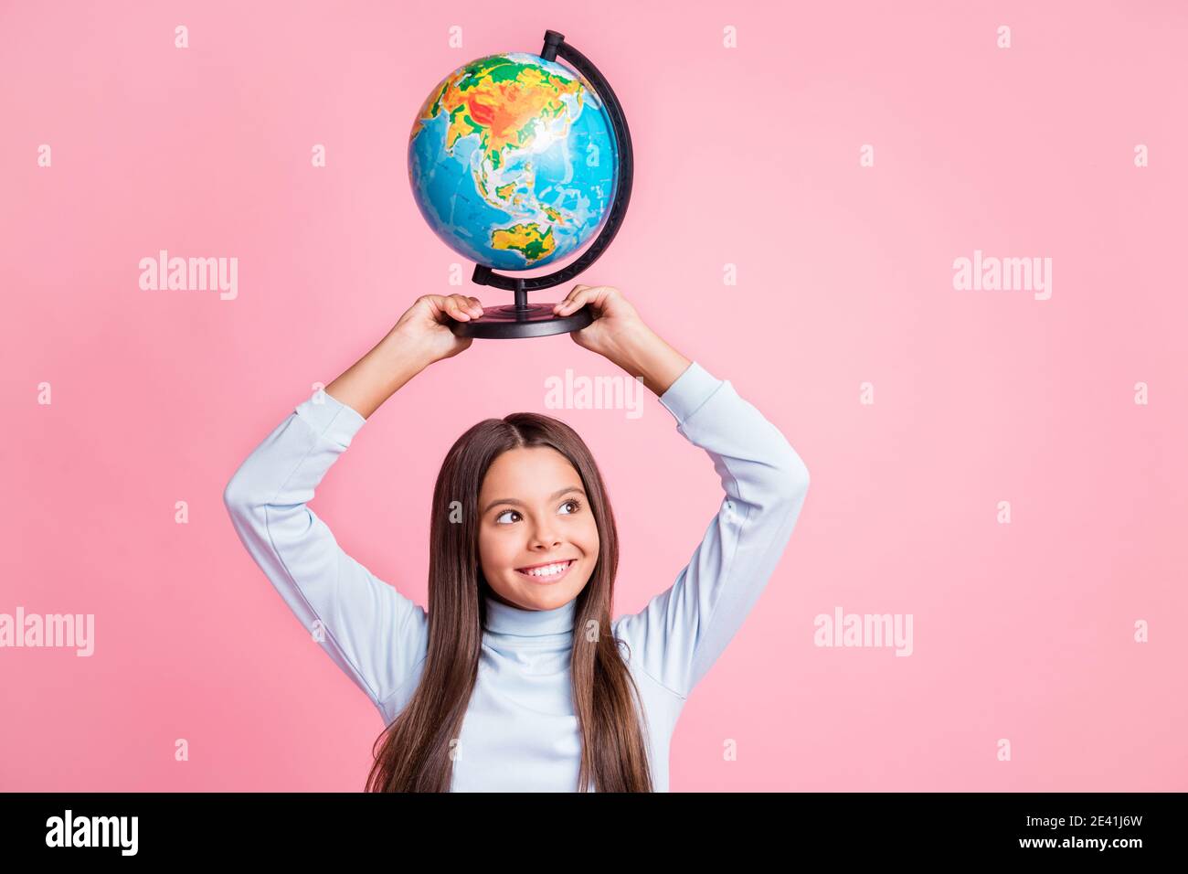 Portrait of attractive cheerful cute girl carrying globe on head ...