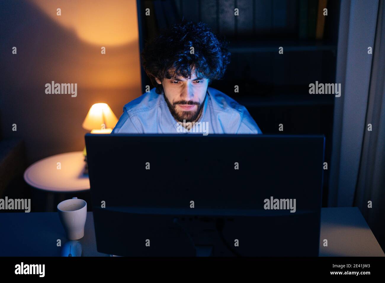 Close-up face of focused bearded man looking intently at monitor screen ...