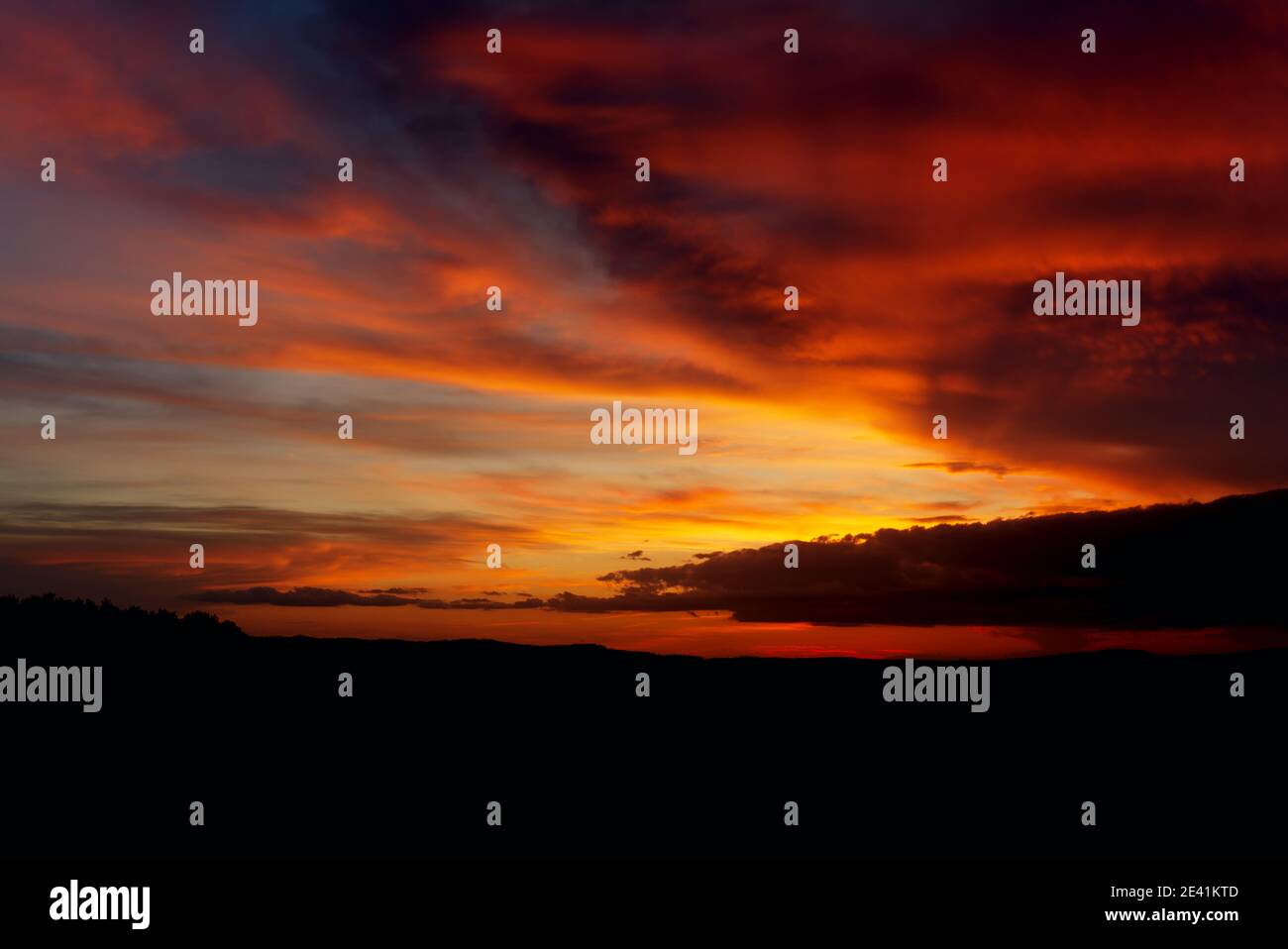 Fiery sunset. Evening sun on the horizon. The clouds are backlit with ...