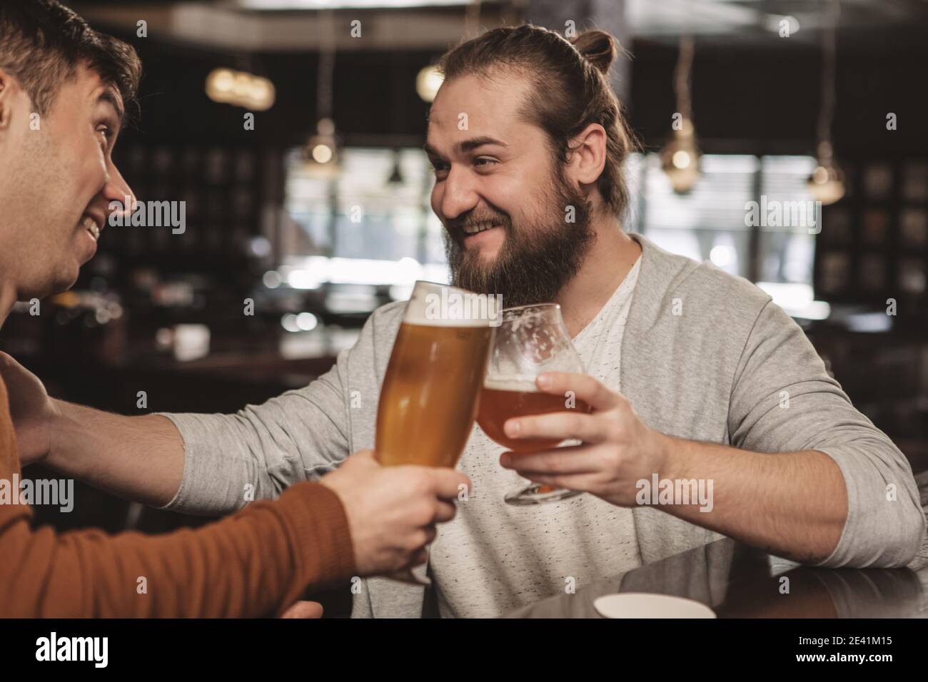 Cheerful bearded man telling jokes to his friend over a glass of beer ...