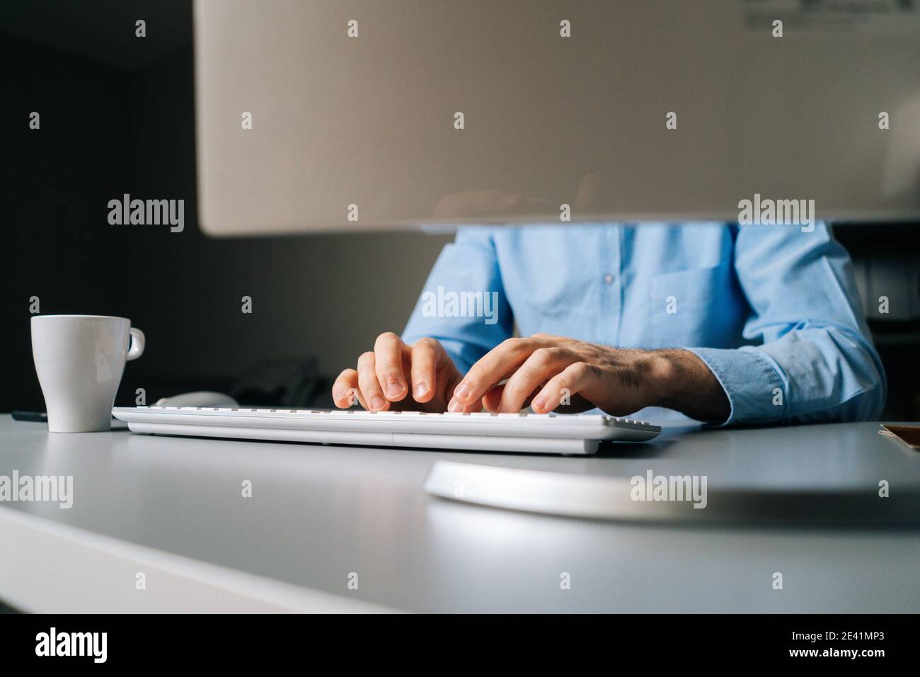 Side View Of Unrecognizable Man Using Computer And Typing Online Message On Wireless Keyboard