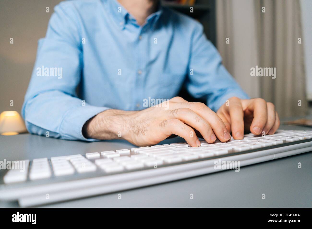 Close-up of unrecognizable man using computer and typing online message on wireless keyboard ...