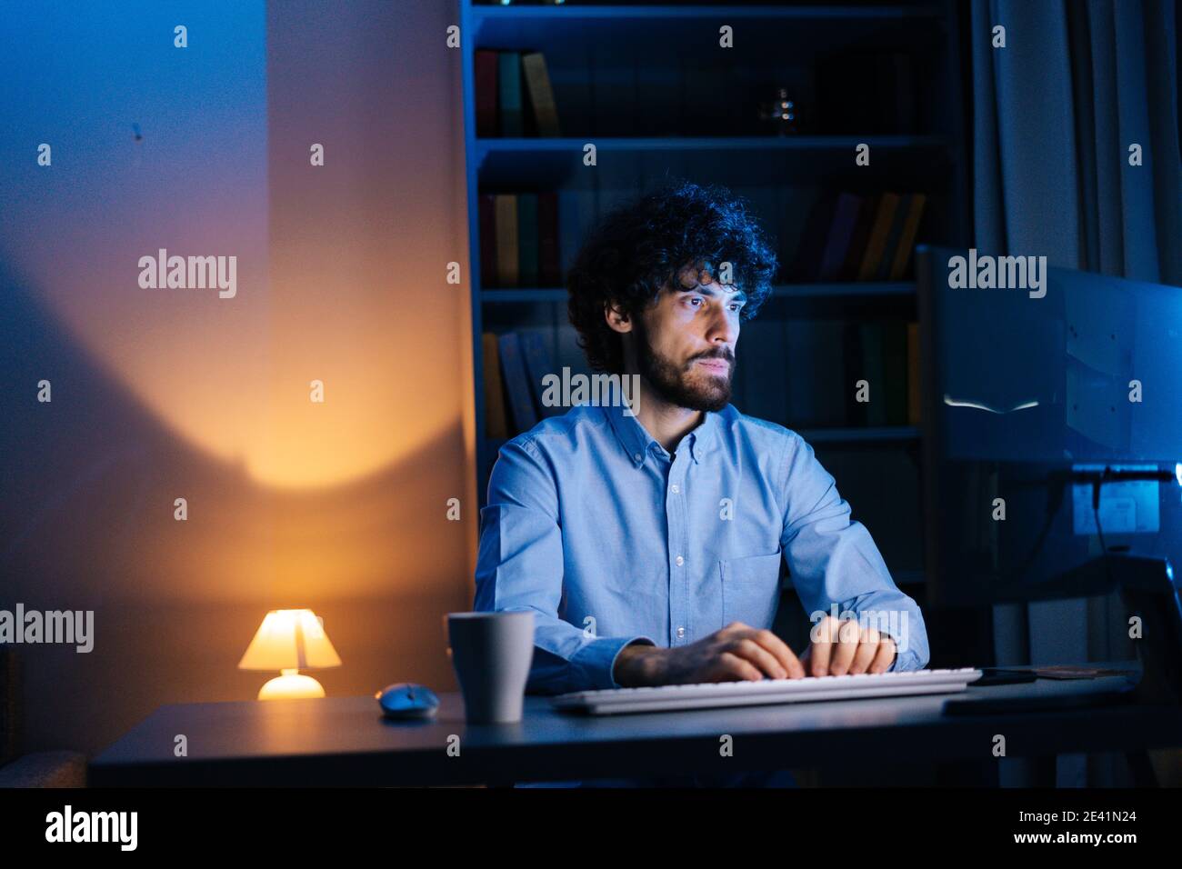 Portrait of smiling man looking intently at monitor screen while ...