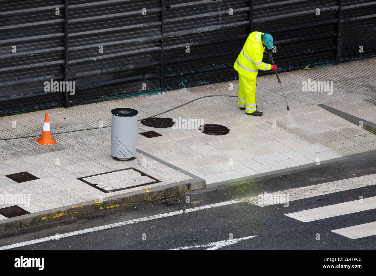 Sweeper Worker cleaning a street sidewalk with high pressure water jet ...
