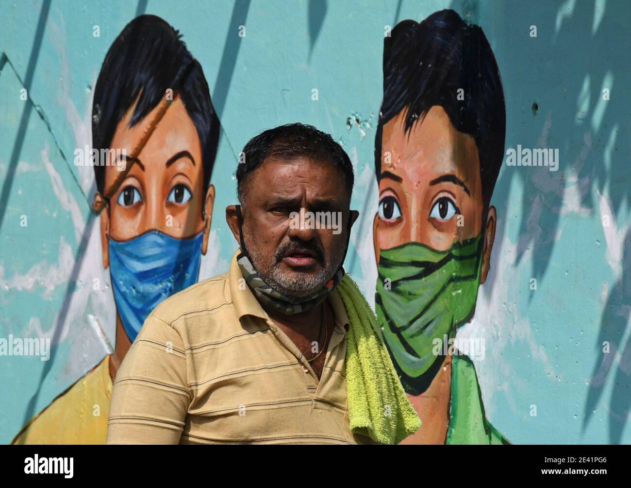 A man with a face mast standing next to a graffiti in Maharashtra ...