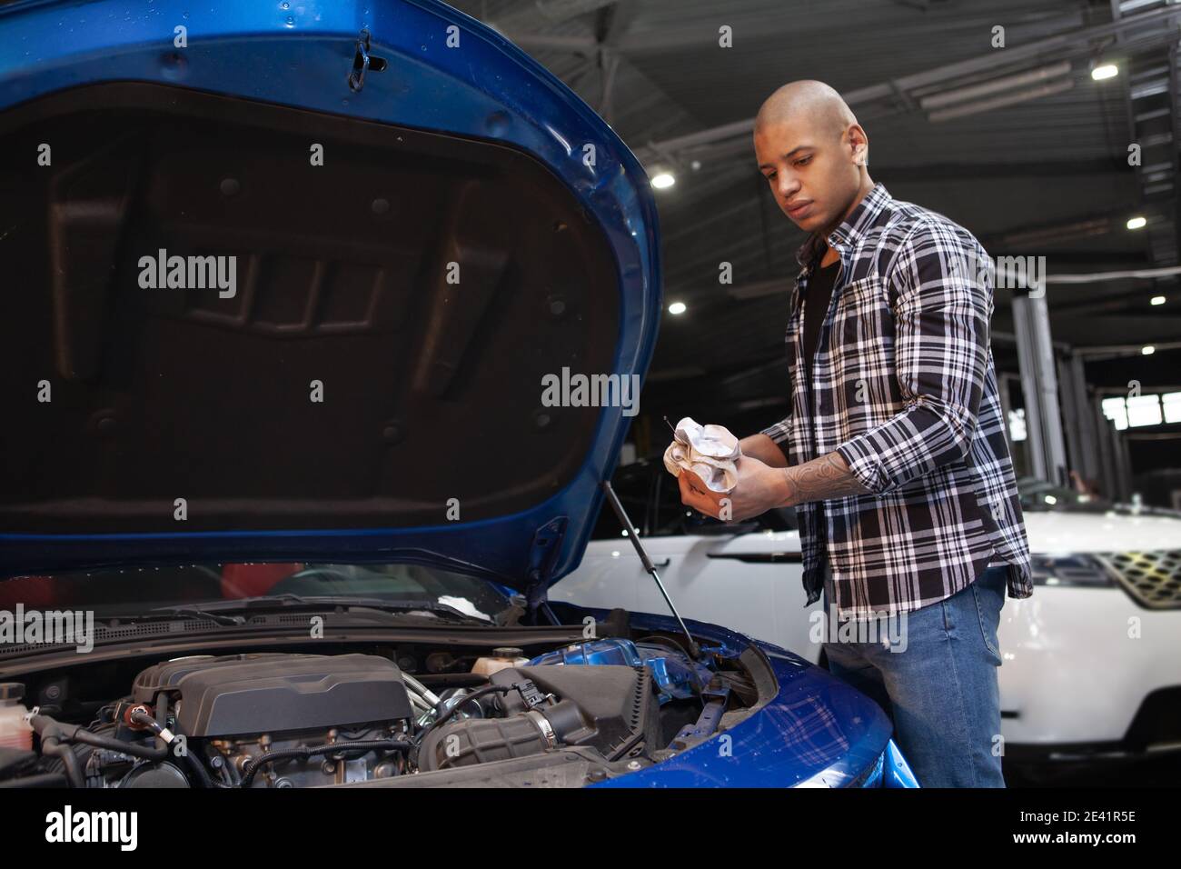 Attractive young African man working on his car at the garage ...