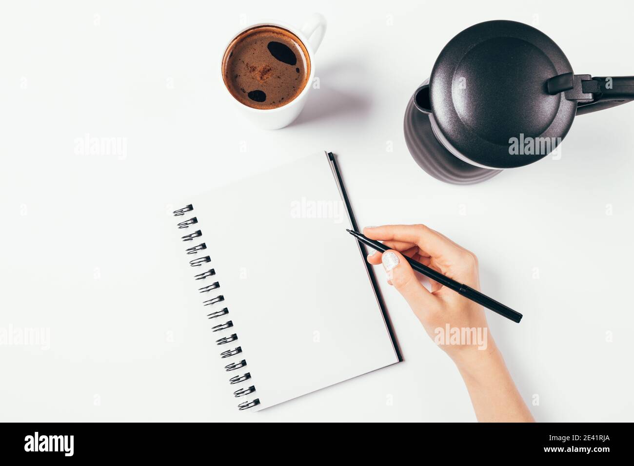Home office workplace with female hand writing in blank paper notebook ...