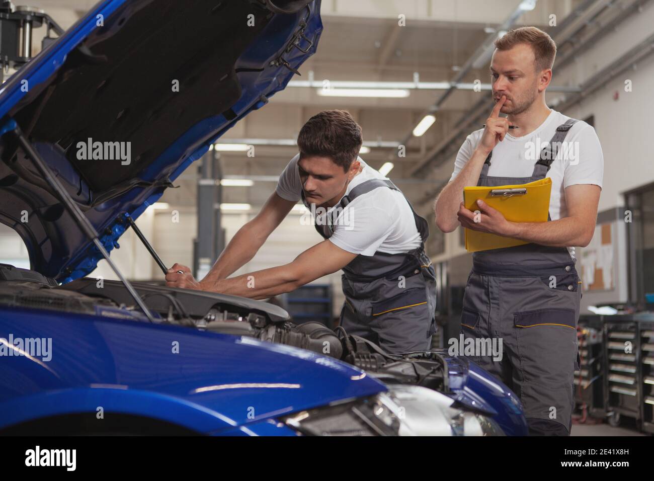 Two male car mechanics repairing broken automobile. Mature auto ...