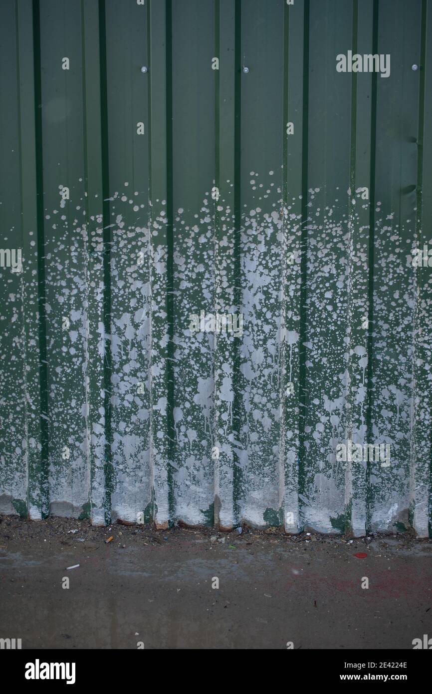 Vertical shot of a metal gate with white paint sprayed on its surface ...