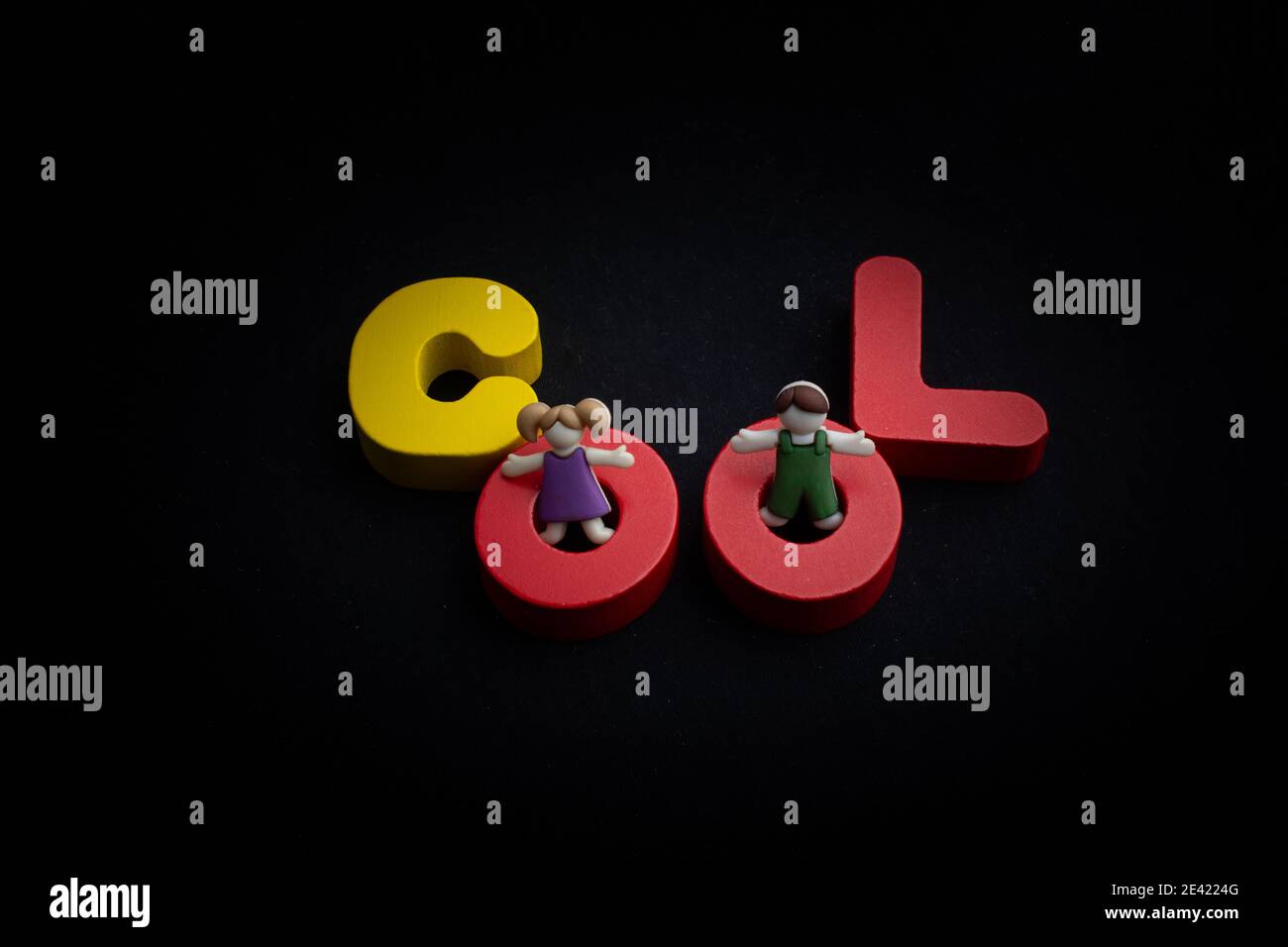 High angle shot of plastic letters saying "Cool" with small figurines ...