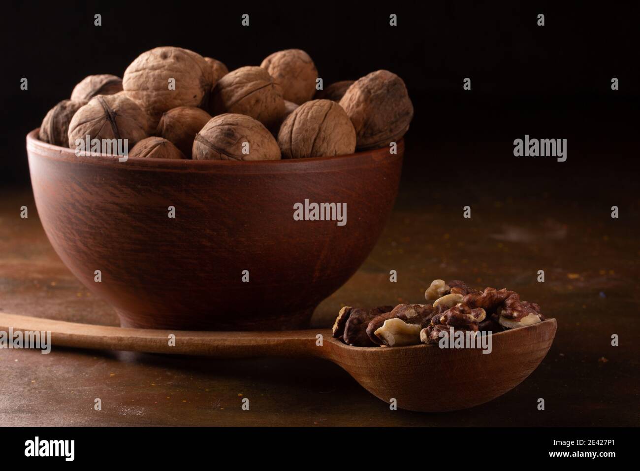 Whole and peeled walnuts in ceramic and wooden dishes on a dark ...