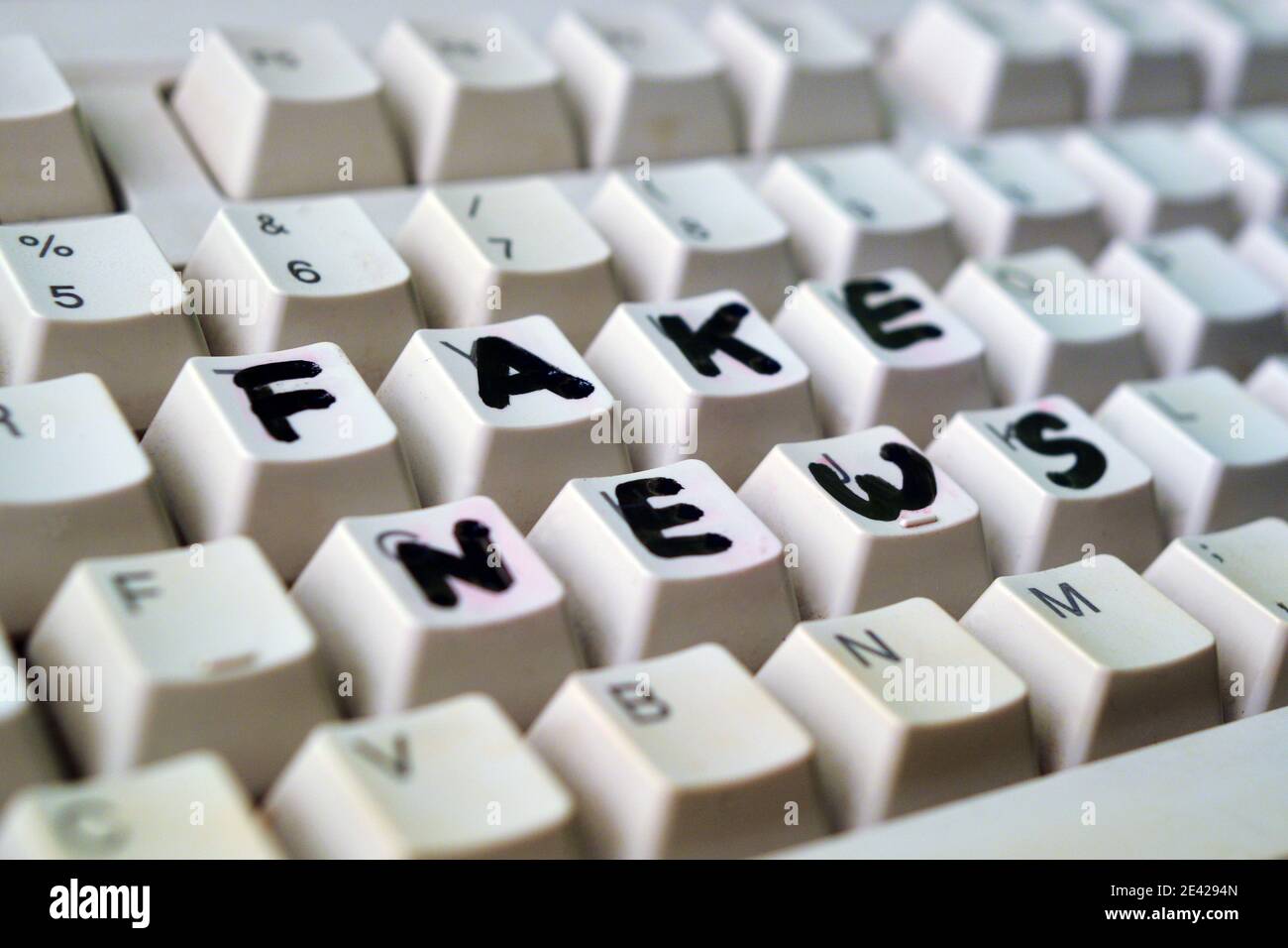 Detail of a computer keyboard with the writing Fake news with a marker ...