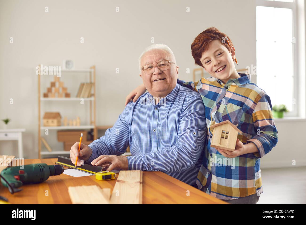 Happy granddad and grandson having fun and making wooden house models ...