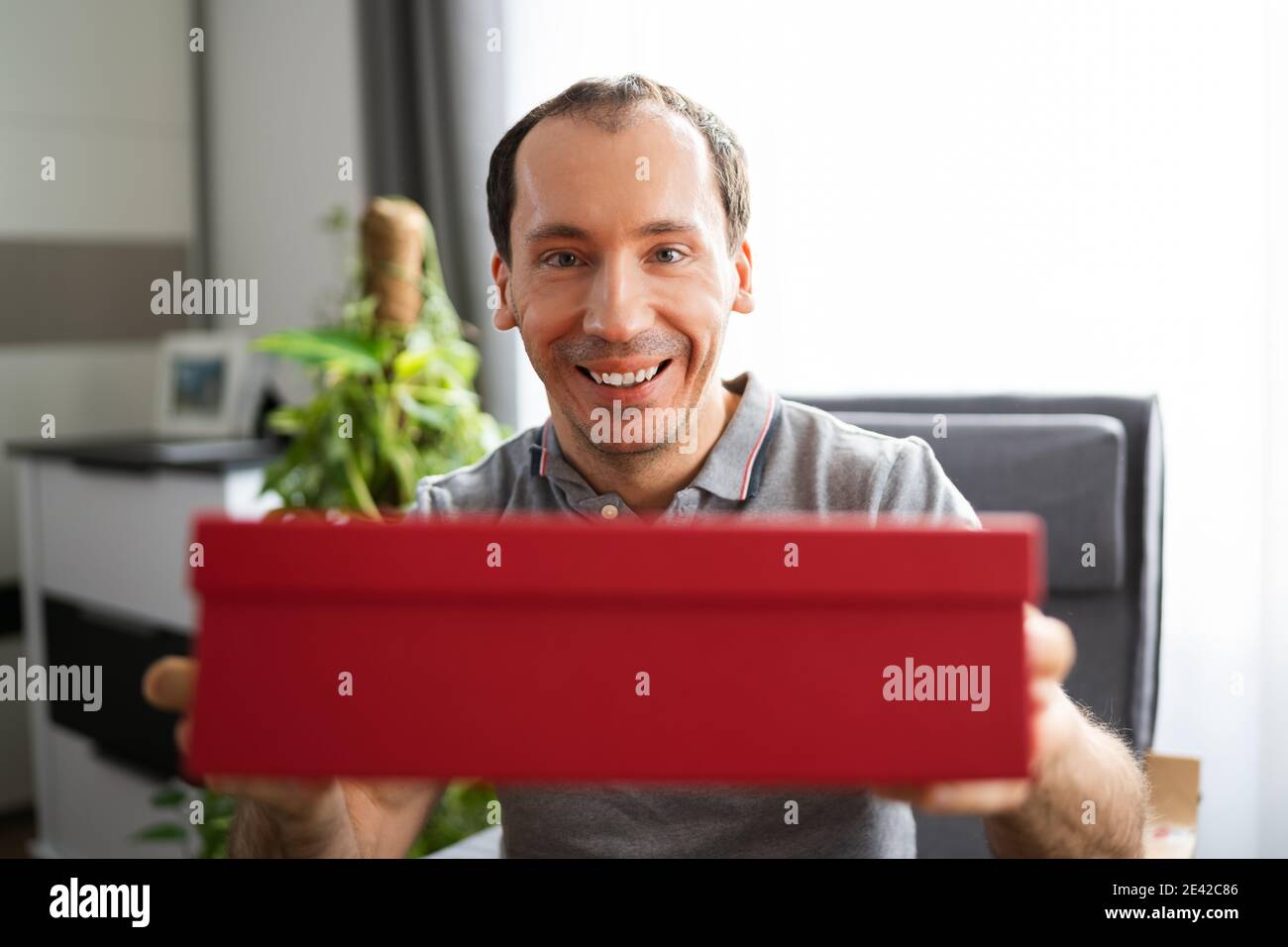 Happy Man Sitting At Home Opening Gift Stock Photo - Alamy