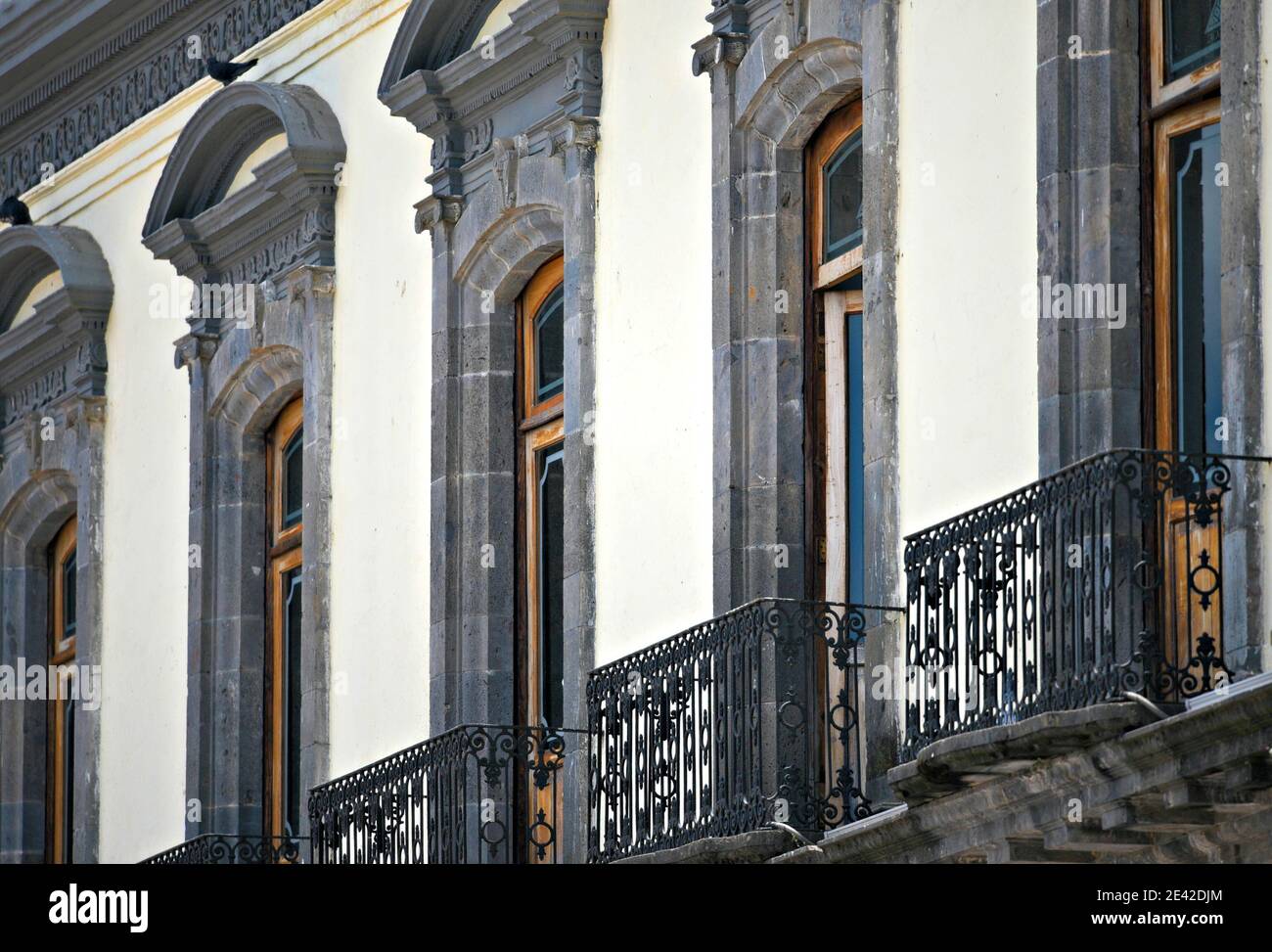 Symmetrical stone trimmed windows and handcrafted iron balcony railings ...