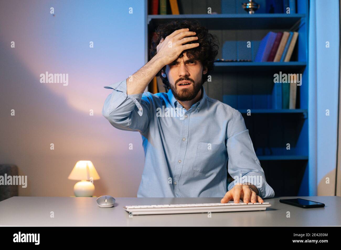 Front view of depressed young man putting hand over forehead sitting ...