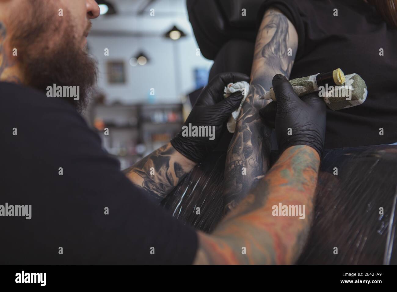 Cropped shot of unrecognizable woman getting her arm tattooed by ...