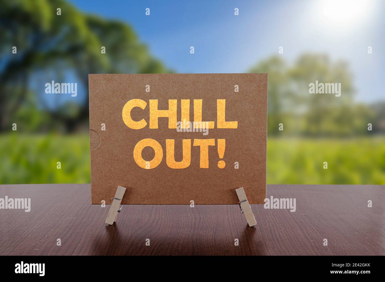Chill out text on card on the table with sunny green park background ...