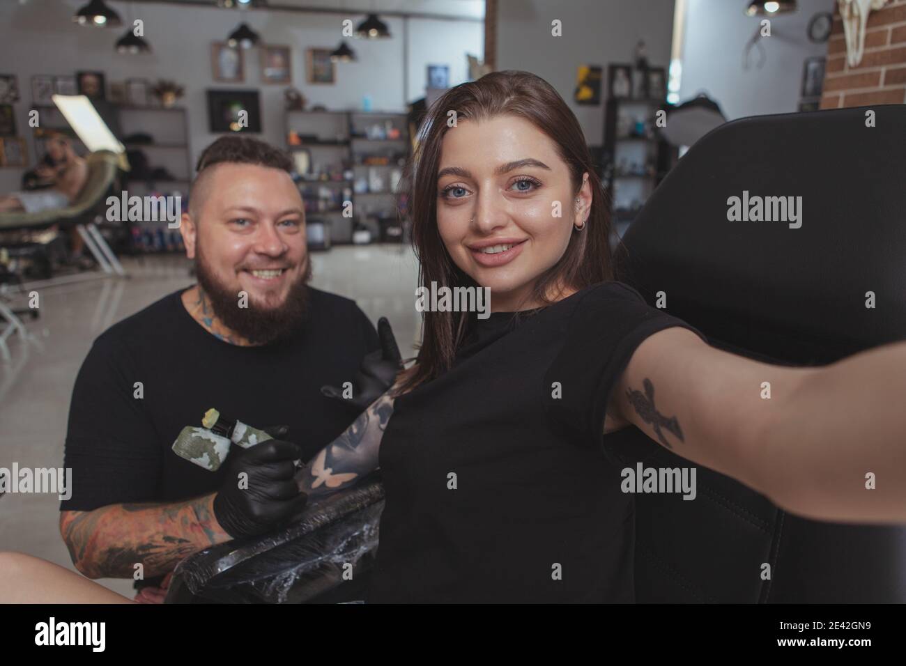 Cheerful Beautiful Young Woman Taking Selfies With Her Tattoo Artist At