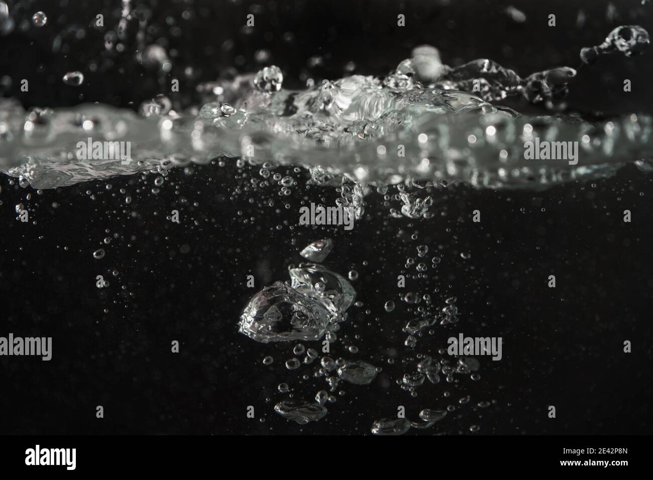 Water splashing as it's poured into aquarium tank, black background ...