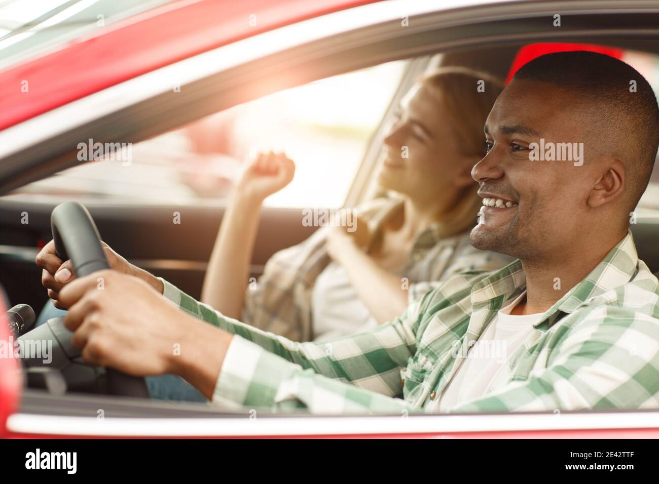 Happy couple travelling by car together. Handsome African man smiling ...