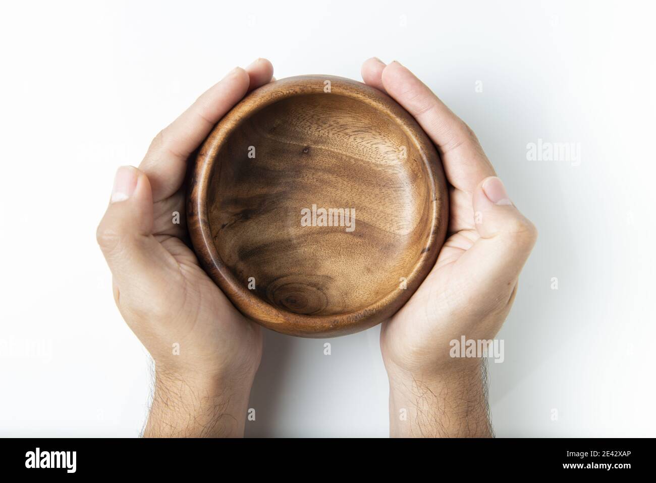 Top view of a person holding a small simple wooden bowl against a white ...