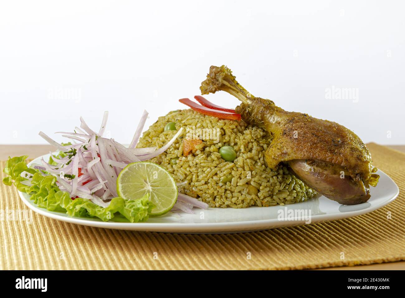Closeup of a plate of typical Peruvian rice with a duck leg accompanied ...