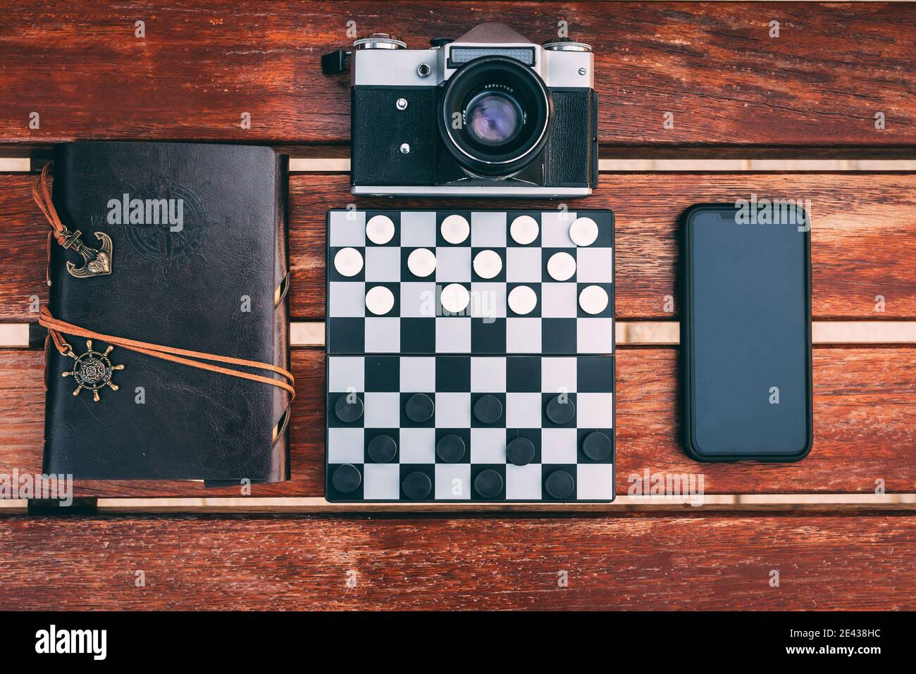 Flat lay of a checker game board, smartphone, camera, and an adventure ...
