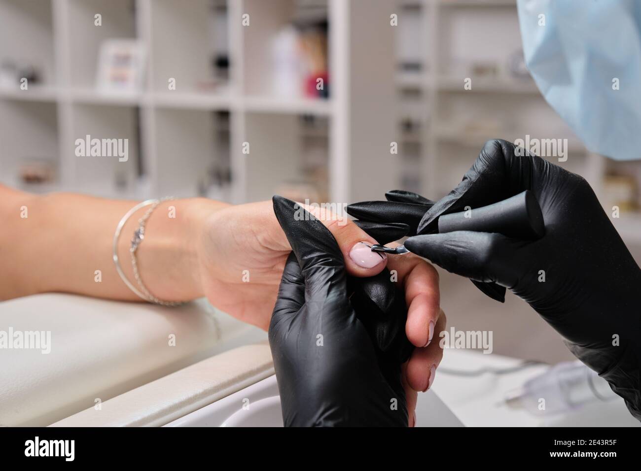 Closeup of crop anonymous master in gloves using metal cuticle pusher ...