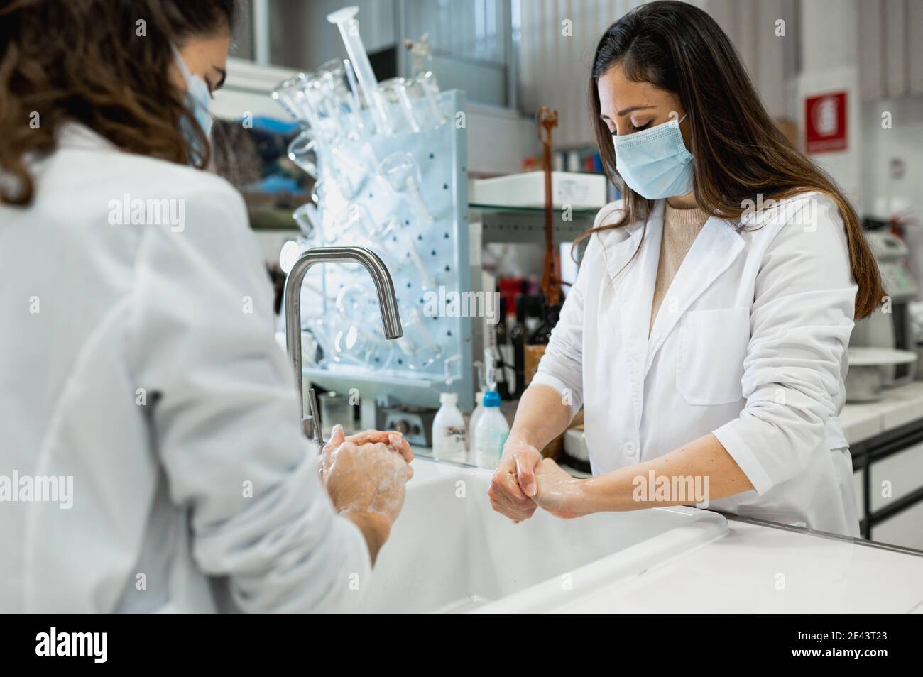 Side view of female scientists in white coats and protective masks ...