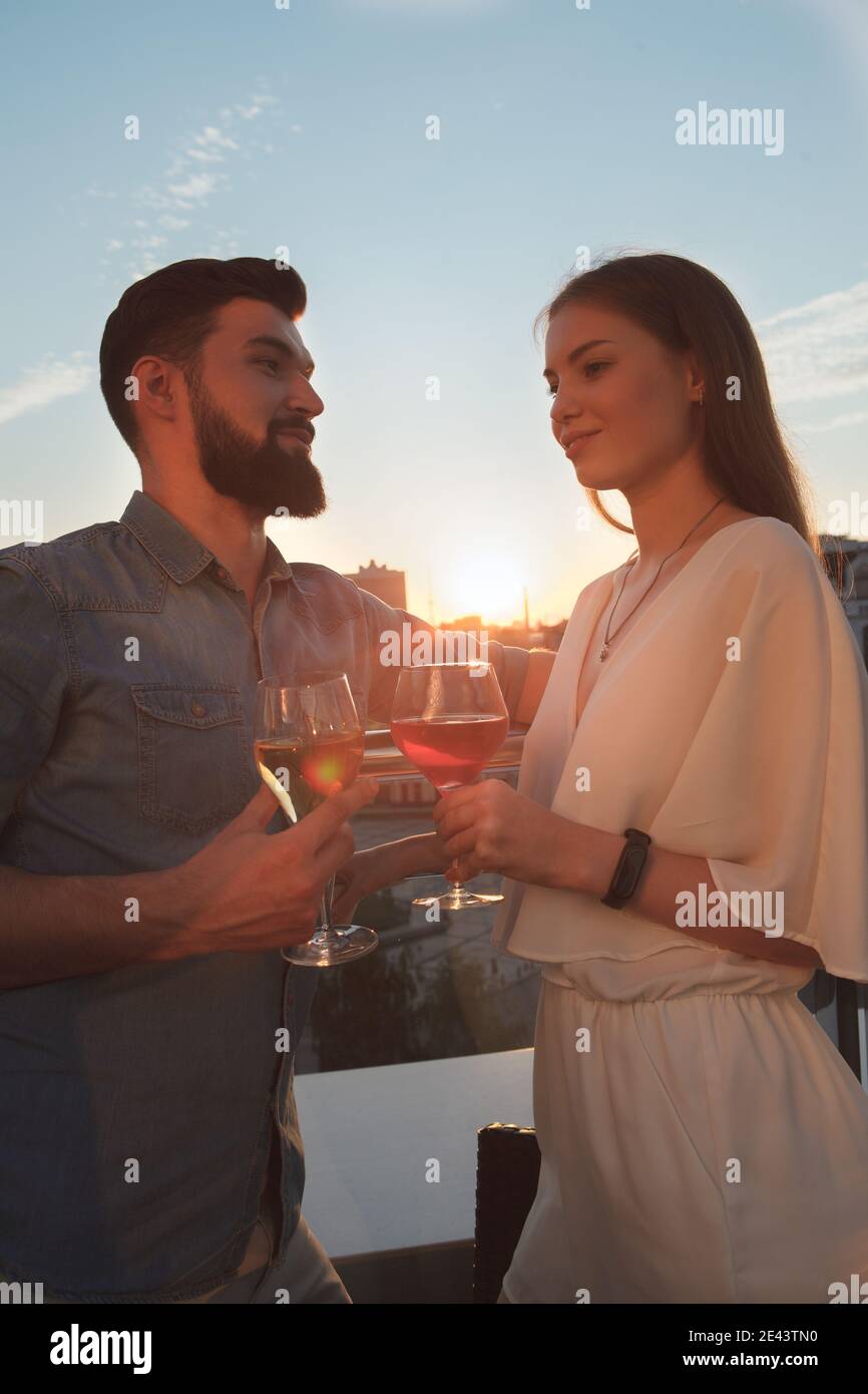 Vertical shot of a young couple talking while drinking wine together on ...