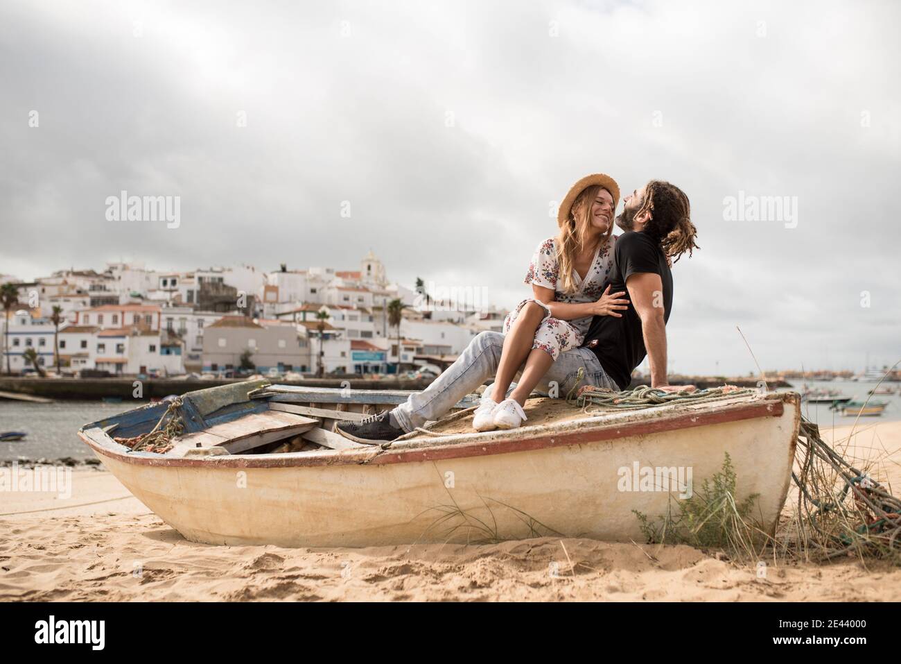 Full body of cheerful young romantic couple relaxing on old wooden boat ...