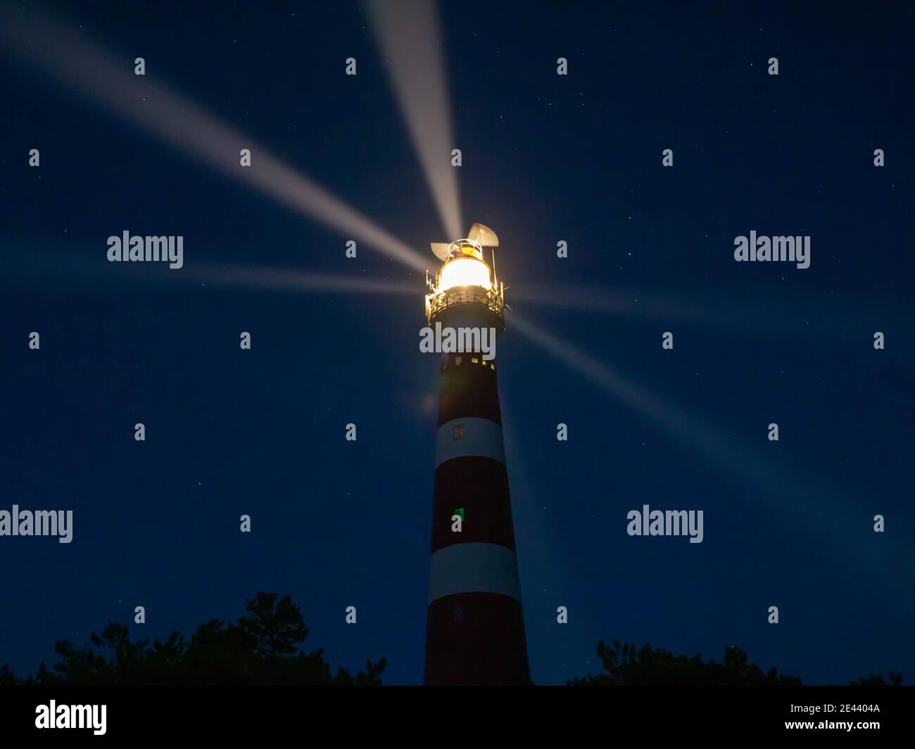 Lighthouse with light rays during night, a starry sky on the island of ...