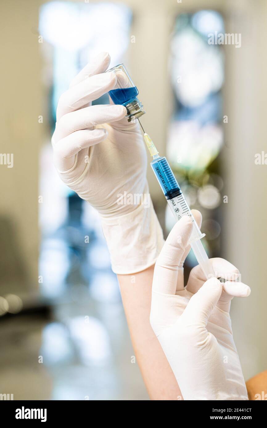 Cropped unrecognizable female doctor in mask and latex gloves filling ...