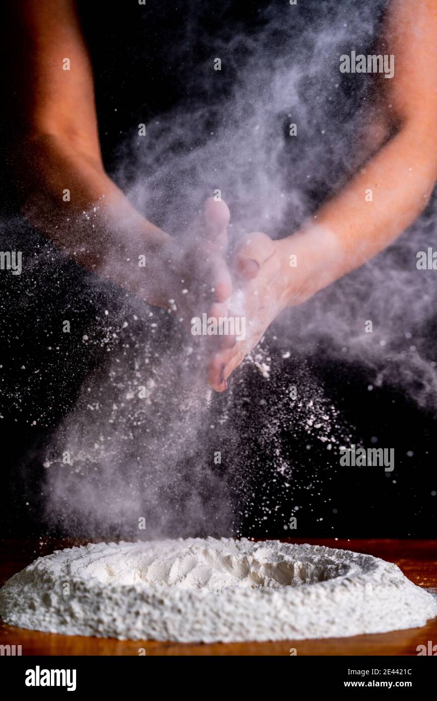 Faceless female baker clapping hands in flour while making bread dough ...