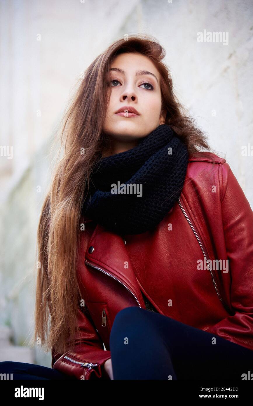 From below self assured young lady with long brown hair in trendy red ...