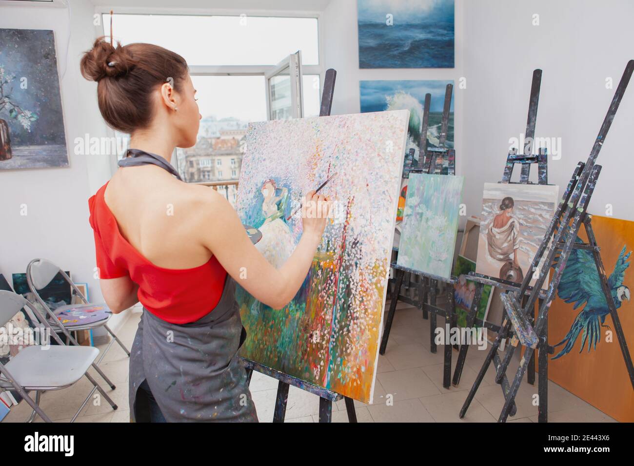 Rear view shot of unrecognizable female artist working on a painting at ...